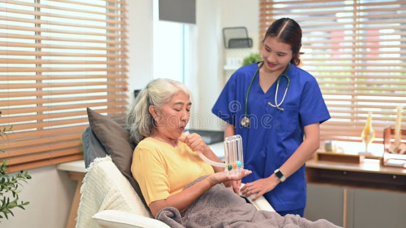 Physical Therapist Assisting Mature Woman with Using a Spirometer To ...