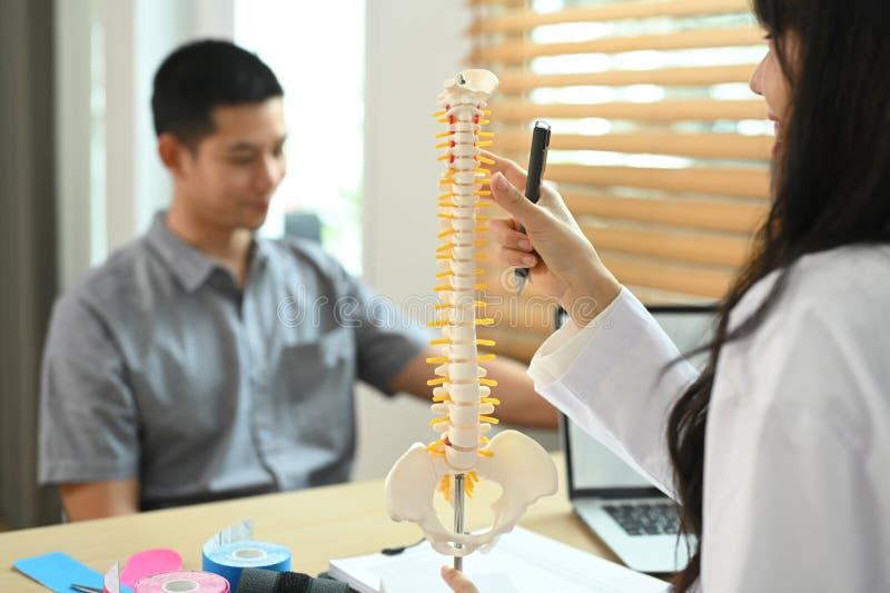 Physical Therapist Educating Male Patient with Spinal Model at ... Physical Therapist Educating Male Patient with Spinal Model at ...