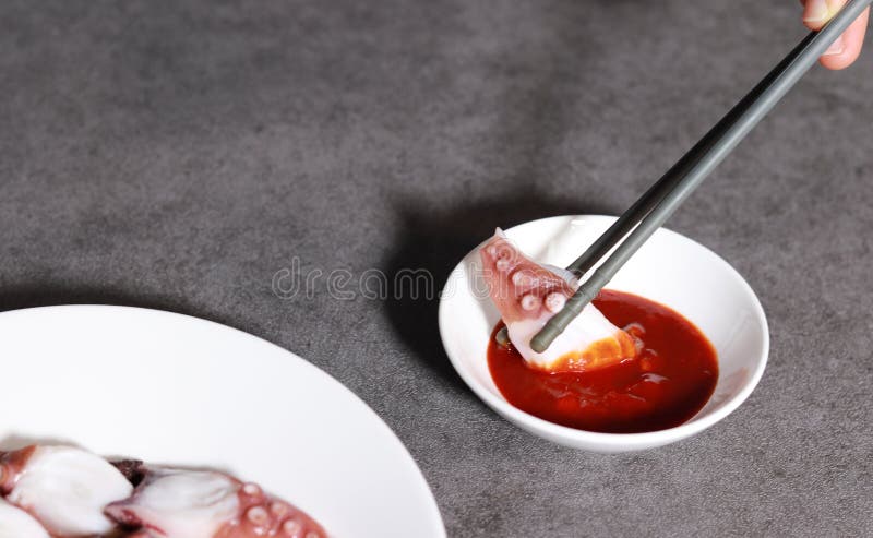 Pick Up the Sliced Octopus with Chopsticks and Dip it in Red Pepper ...