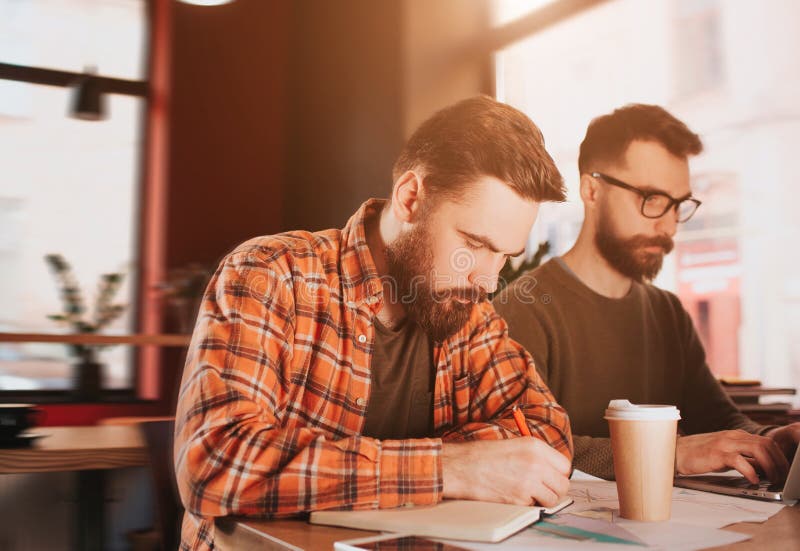 A Picture of Bearded Guy Writing Down Notes in His Notebook while His ...