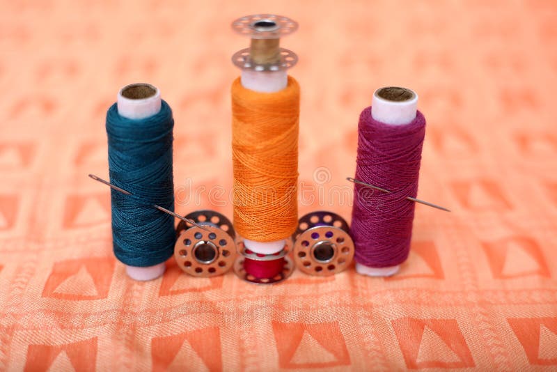 Picture of Sewing Thread and Bobbin with Needle on the Orange Cloth ...