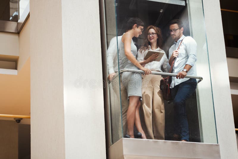 Picture of Young Businesspeople Talking in Elevator Stock Image - Image ...