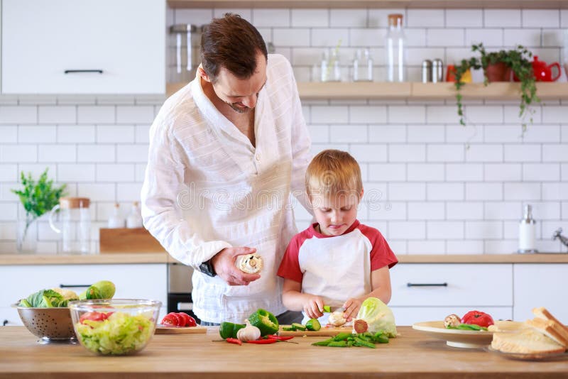 Picture of Young Father and Son Cooking at Table with Vegetables Stock ...
