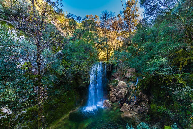 Picturesque Waterfall Cascading Over Moss-covered Rocks into a Serene ...