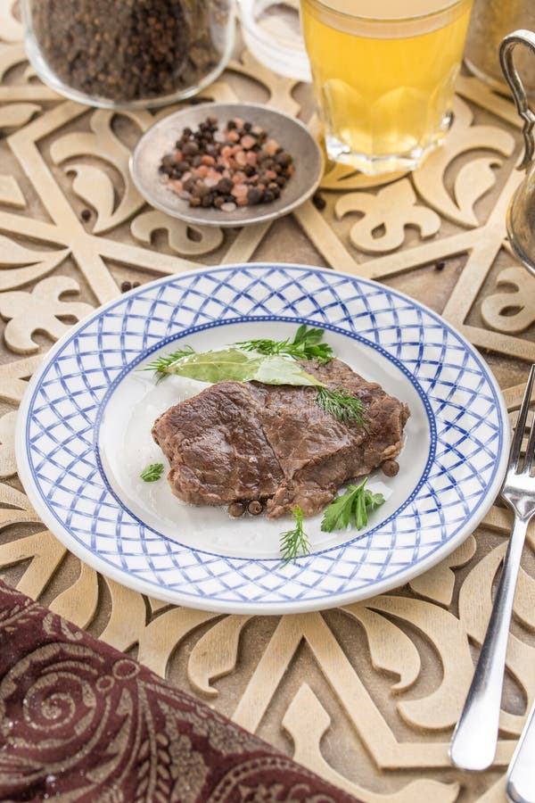 Piece of Boiled Beef on a Plate with Broth and Herbs on Oriental Wooden ...