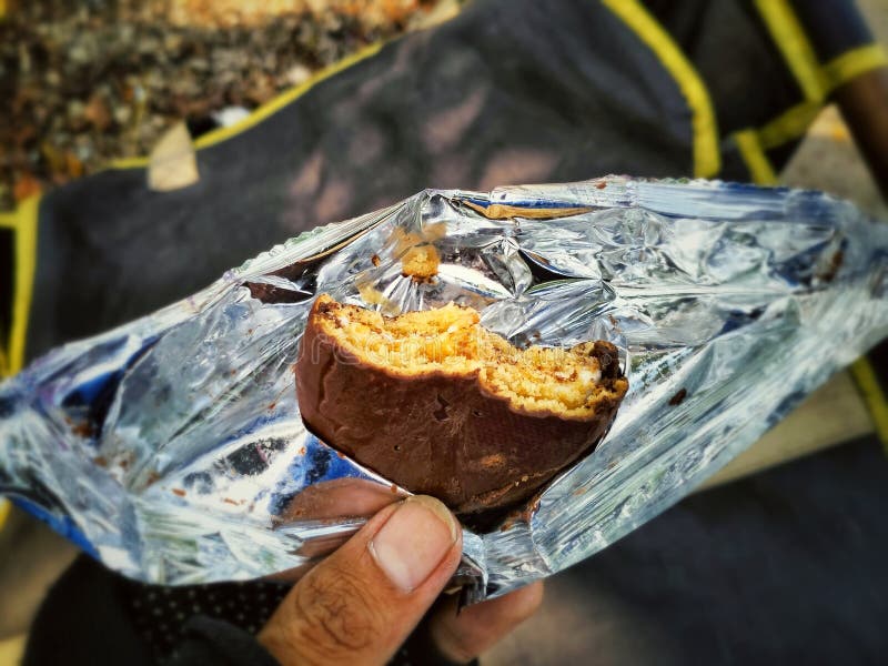 A Piece of Chocolate Biscuit in Hand with a Silver Wrapper Stock Image ...