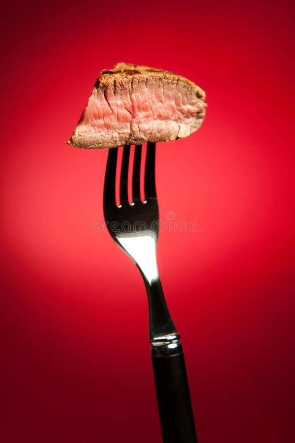 Piece of a Grilled Steak on a Fork Isolated on Red Stock Image - Image ...