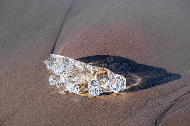 . a Piece of Ice that Rests on a Sandy Surface and Has a Shadow Stock ...