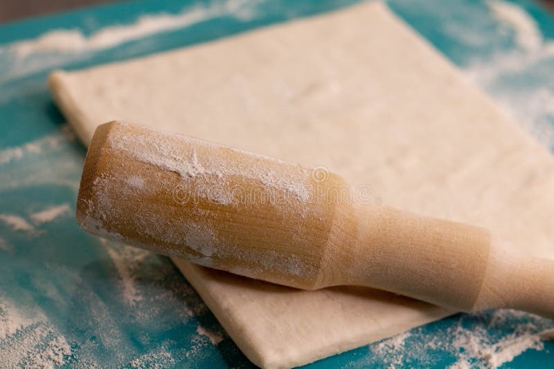 A Piece of Puff Pastry and a Wooden Rolling Pin on a Turquoise Board ...