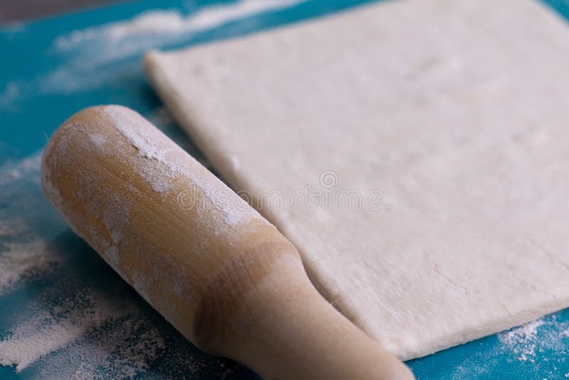 A Piece of Puff Pastry and a Wooden Rolling Pin on a Turquoise Board ... A Piece of Puff Pastry and a Wooden Rolling Pin on a Turquoise Board ...