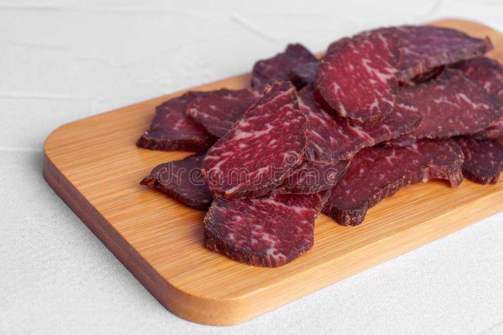 Pieces of Delicious Beef Jerky on White Textured Table, Closeup Stock ...