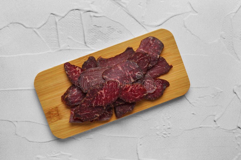 Pieces of Delicious Beef Jerky on White Textured Table, Top View Stock ...