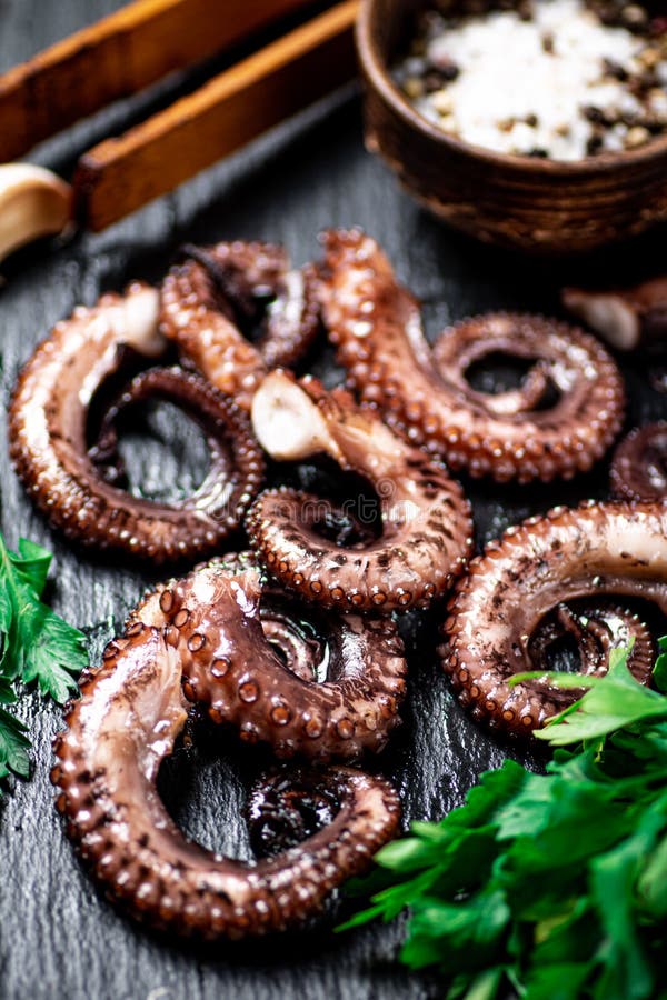 Pieces of Fresh Octopus on a Stone Board with Greenery. Stock Image ...