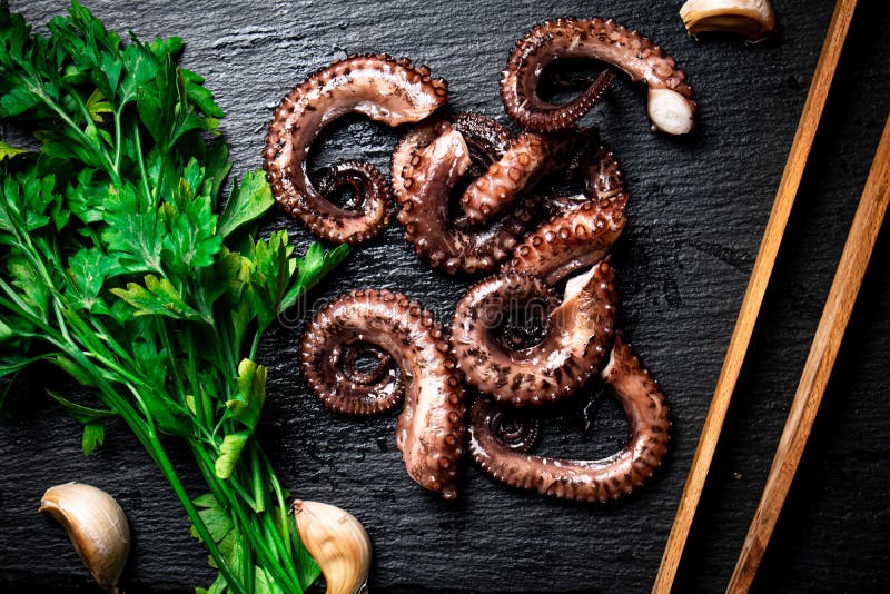 Pieces of Fresh Octopus on a Stone Board with Greenery. Stock Image ...