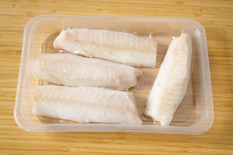 Pieces of Frozen Cod Fish Fillets in Vacuum Plastic Tray on the Wood ...