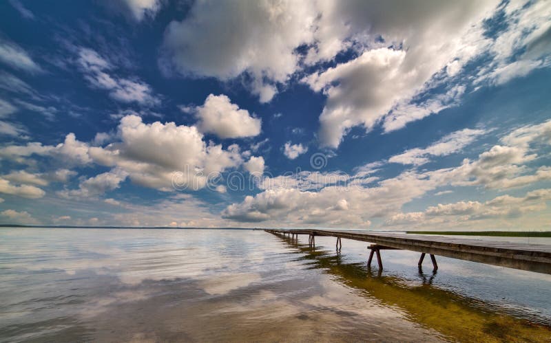 Pier in Large Lake Under Blue Sky and Clouds Stock Image - Image of ...
