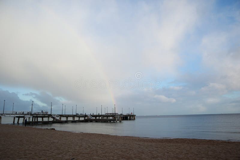 Pier on the Sea Beach. Cloudy Sky with Rainbow. Rainbow on the Sea in ...
