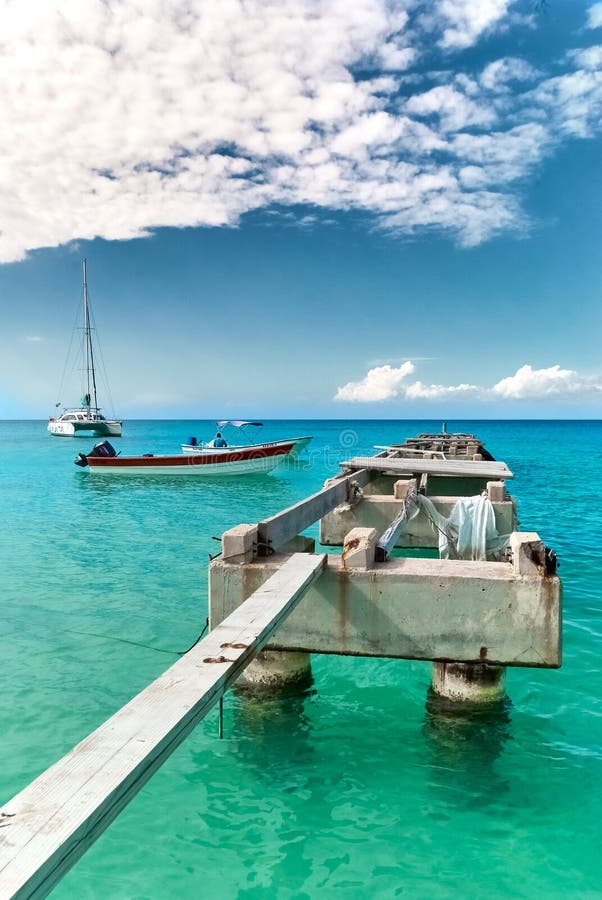 Pier on the Shore of the Beach with Boats Tied Around Stock Image ...
