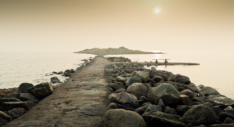 Pier Surrounded by Stones Going through the Calm Sea with the Sunny Sky ...