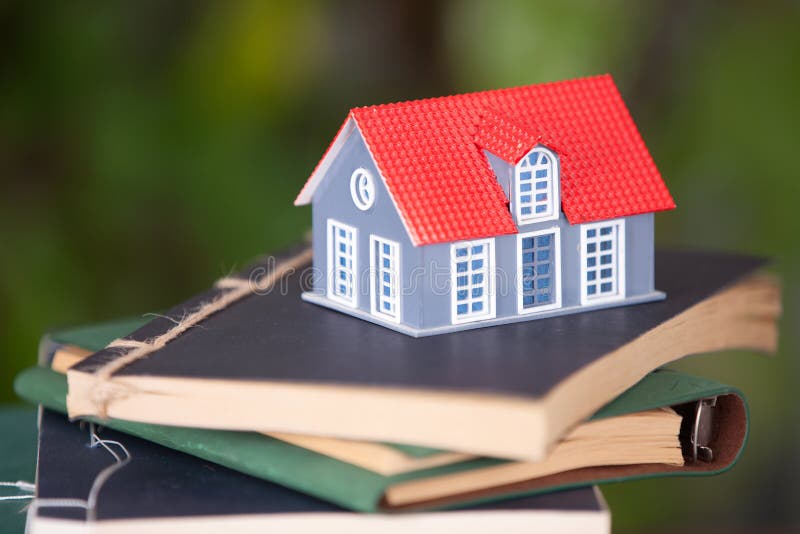 A Pile of Books and a Model of a Small House Stock Photo - Image of ...
