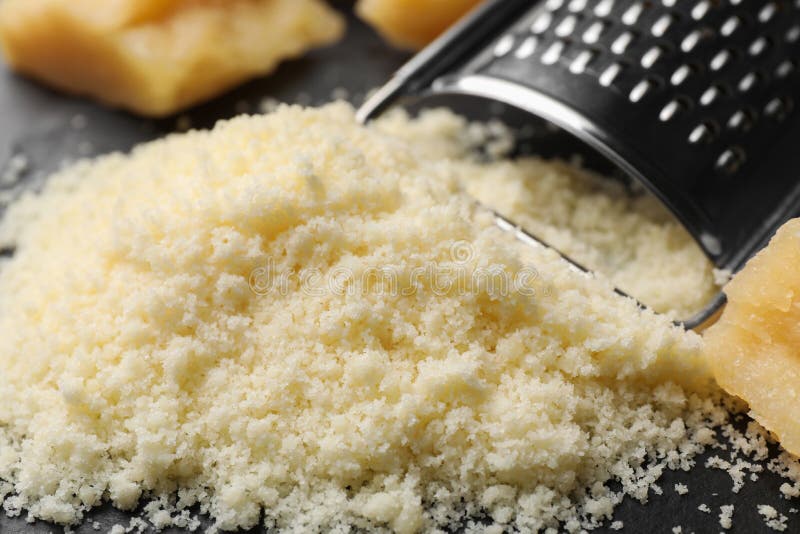 Pile of Grated Parmesan Cheese and Grater on Black Table, Closeup Stock ...