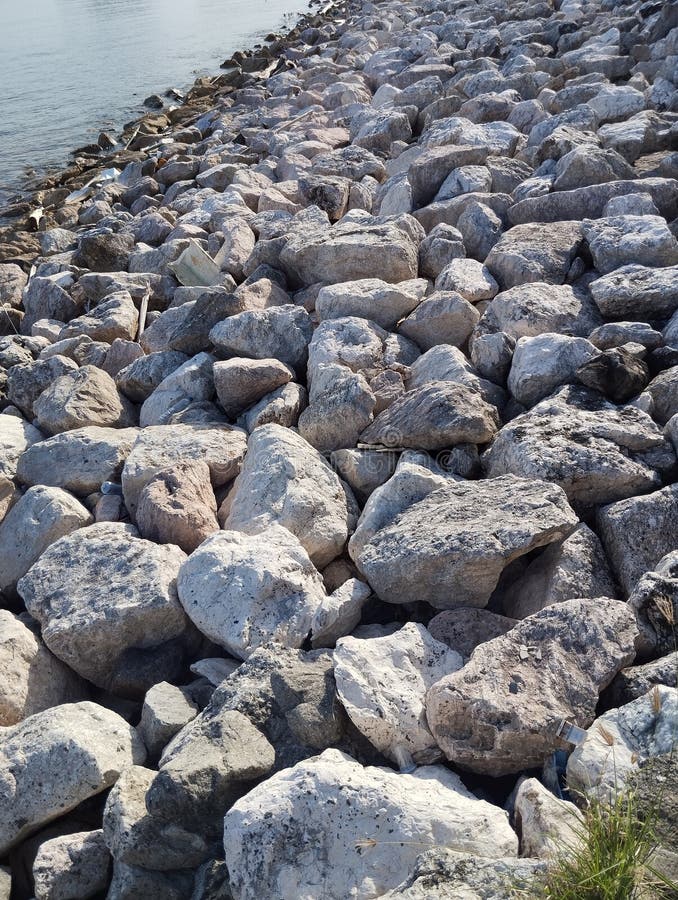 A Pile of Large, Irregularly Shaped Mountain Rocks Forms a Riprap Along ...