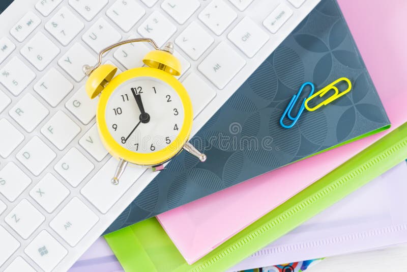 A Pile of Office Folders, Lying with an Alarm Clock Set at Five To ...