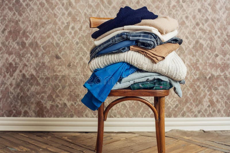 Pile of Old Clothes Stacked on Chair in Old Room with Wall Background ...