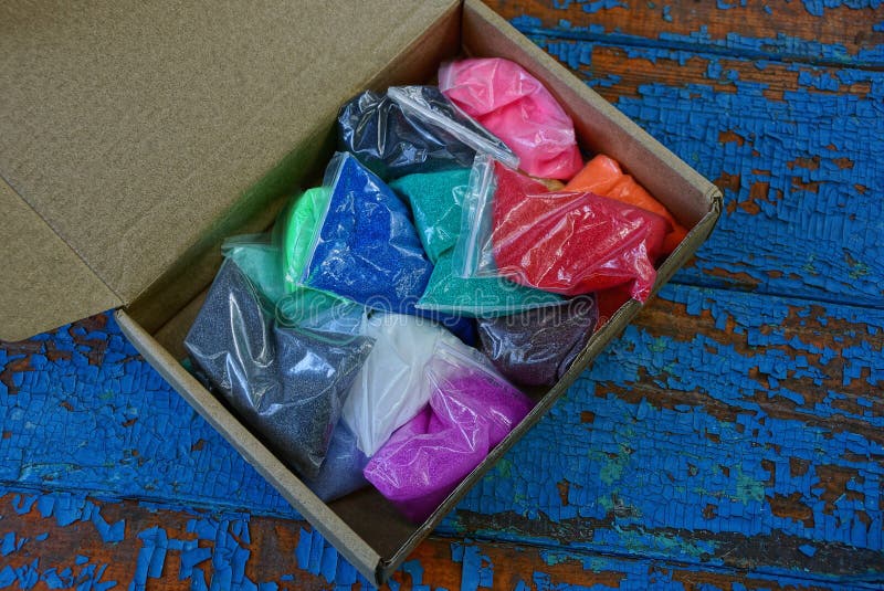 Plastic Bags with Colored Sand in an Open Paper Box Stands on a Blue ...