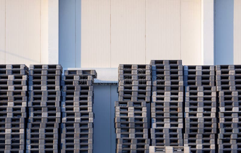 Pile of Plastic Pallets Stacked in Front of White Wall of Industrial ...