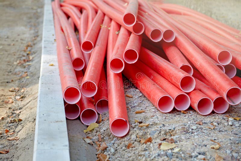Pile of Plastic Red Water Pipes at a Construction Site. Laying Utility ...