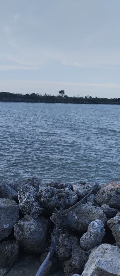 A Pile of Rocks on the Edge of the Ocean in the Late Afternoon with a ...