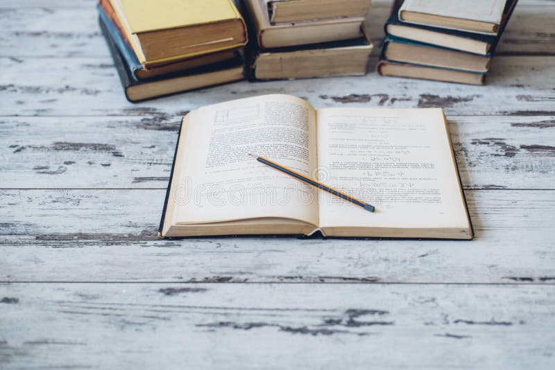 Piles of Books with One Book Open and Pencil Lzing on Its Pages Stock ...