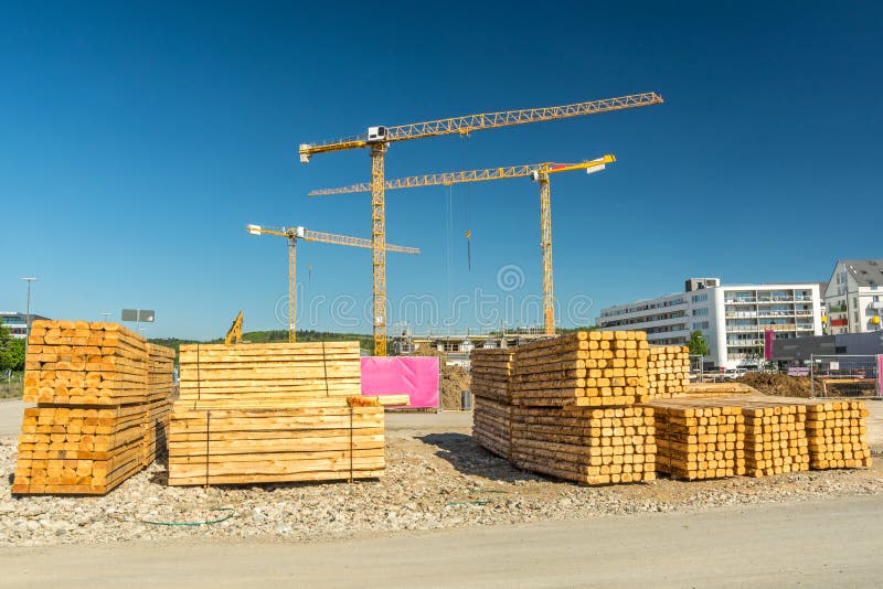 Piles of Wood in Front of Large Construction Site with Cranes Stock ...