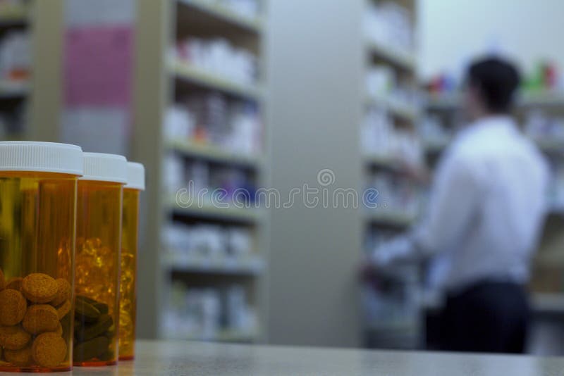 Pill Bottles on a Pharmacy Counter with Pharmacist in Background Stock ...