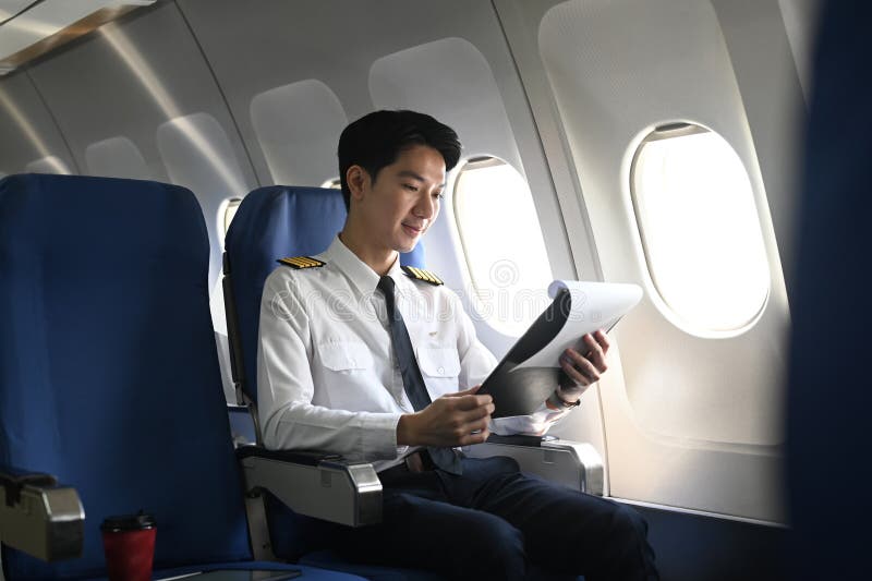 Pilot with Clipboard Sitting Near a Window in an Airplane and Checking ...