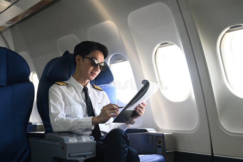 Pilot with Clipboard Sitting Near a Window in an Airplane and Checking ...