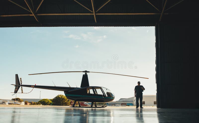 Pilot with a Helicopter in Airplane Hangar Stock Image - Image of ...