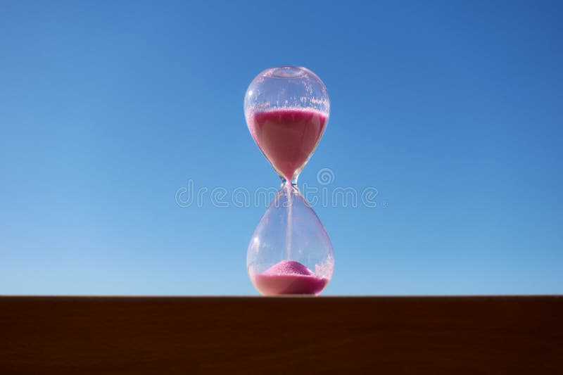 Pink hourglass on blue sky stock photo. Image of timekeeping - 327555070