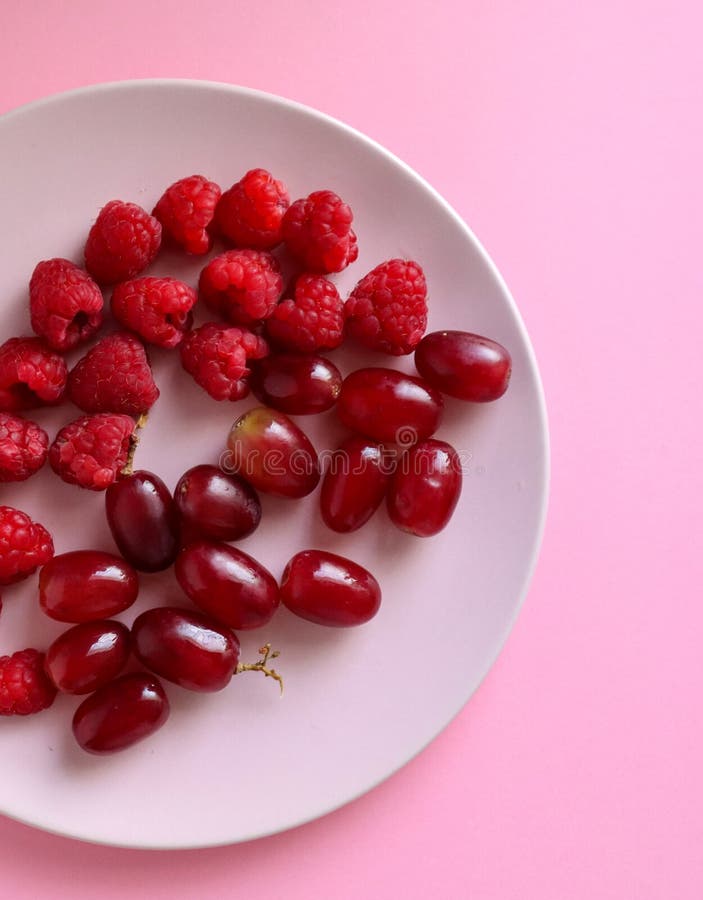 Pink Plate of Various Fruit Including Raspberries and Red Grapes Stock ...