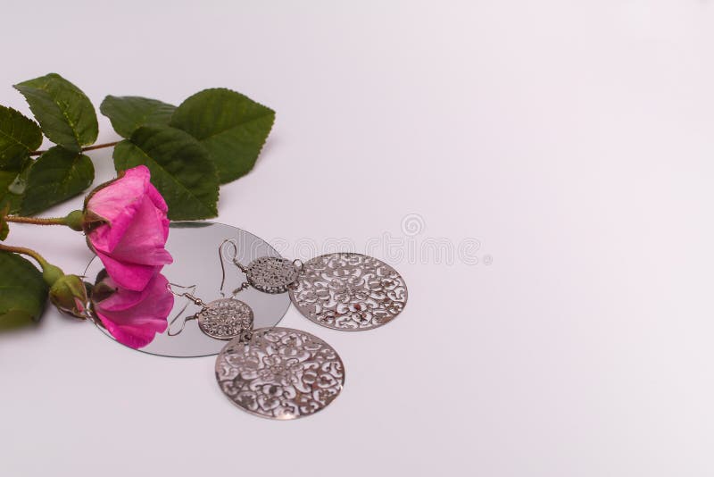 Pink Rose on the Mirror with Large Earrings on a White Background. Mock ...