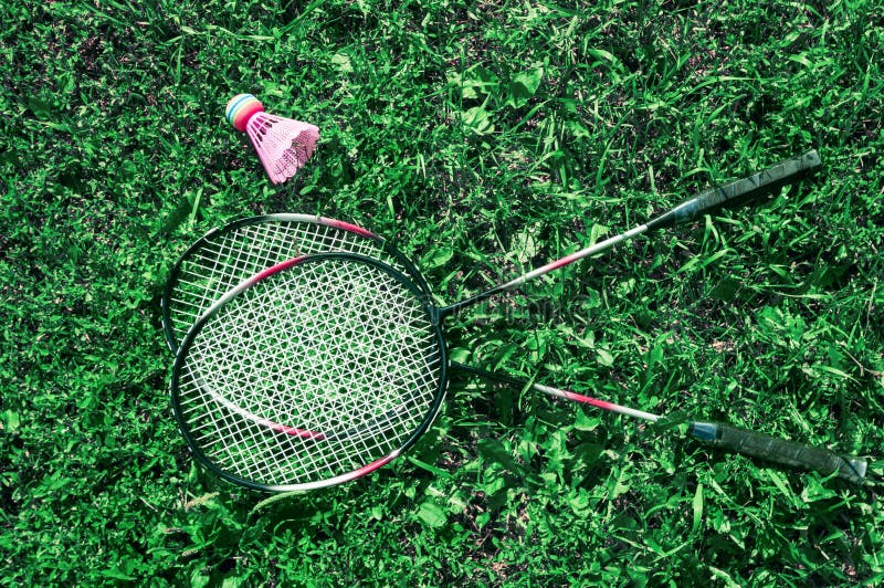 A Pink Shuttlecock and a Badminton Racket on the Green Lawn Grass ...