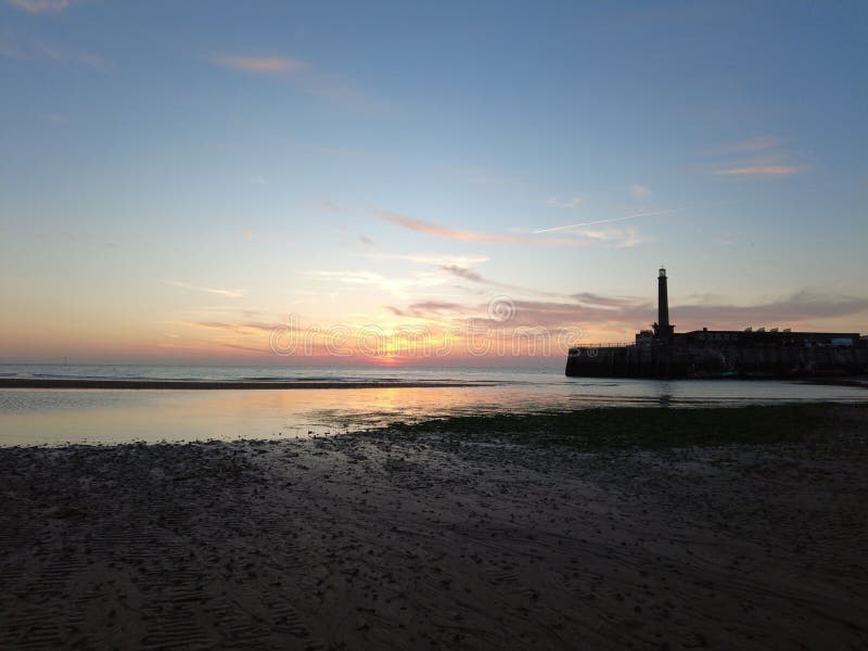 Pink Sunset Shining Behind the Calm Sea and the Silhouette of a ...