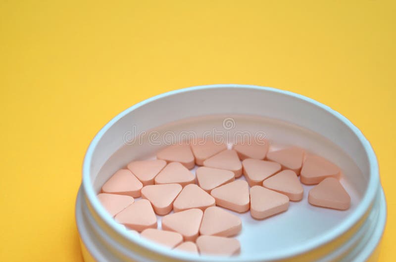 Pink Triangular Unusual Pills in a White Round Box on a Yellow ...