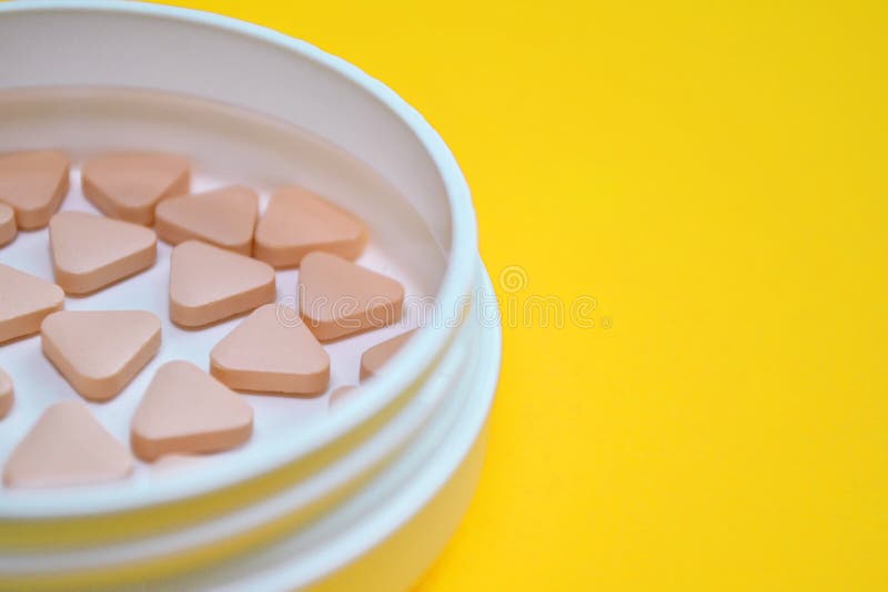 Pink Triangular Unusual Pills in a White Round Box on a Yellow ...