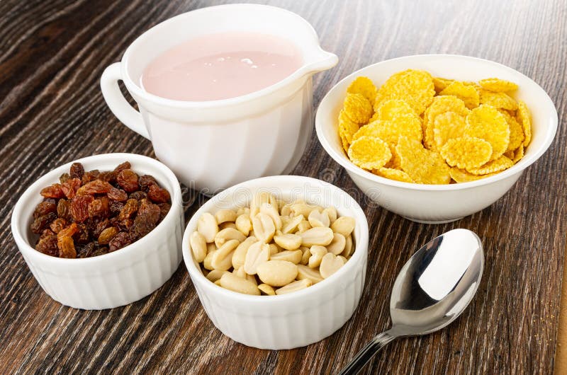 Pitcher with Yogurt, Bowls with Raisin, Peanut, Corn Flakes on Wooden ...