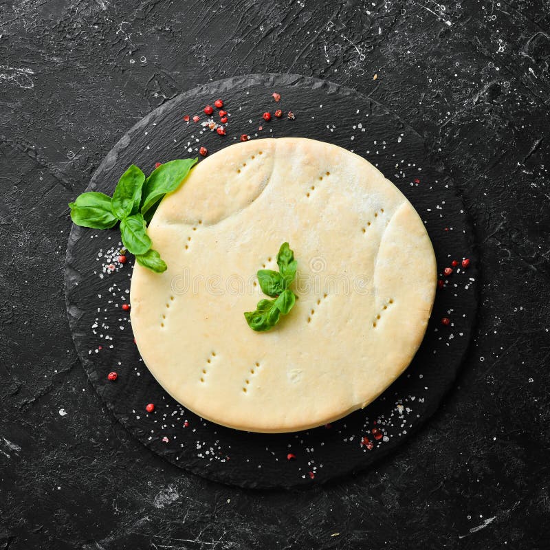 Pizza Base on a Black Stone Plate with Basil. Stock Image - Image of ...