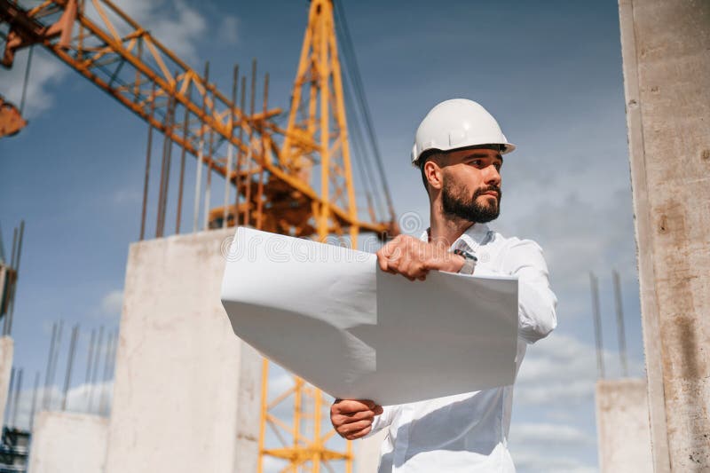 With Plan in Hands. Man in Uniform is Working on the Construction Site ...