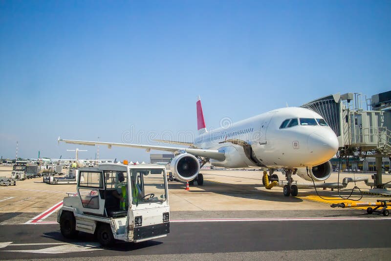 Plane at the Airport during Loading Passengers. Near the Tractor Stock ...