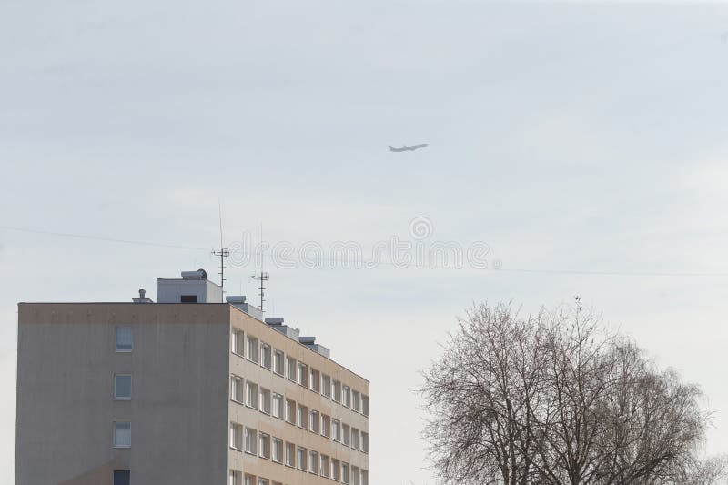 A Plane Flies Over a Tall Building with a Tree in Front Stock Photo ...